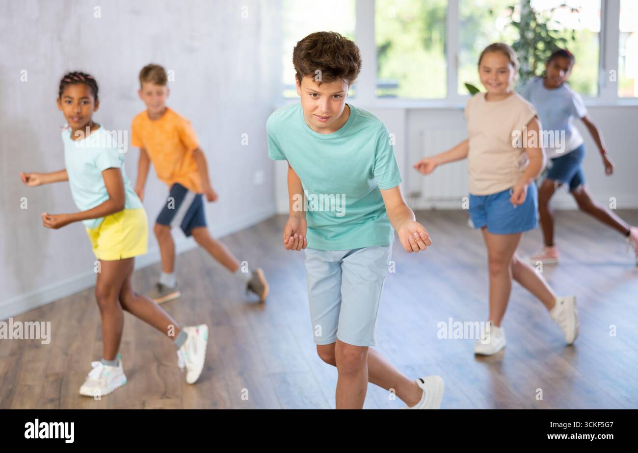 Cheerful tween boy dancing with group of children in choreography class ...
