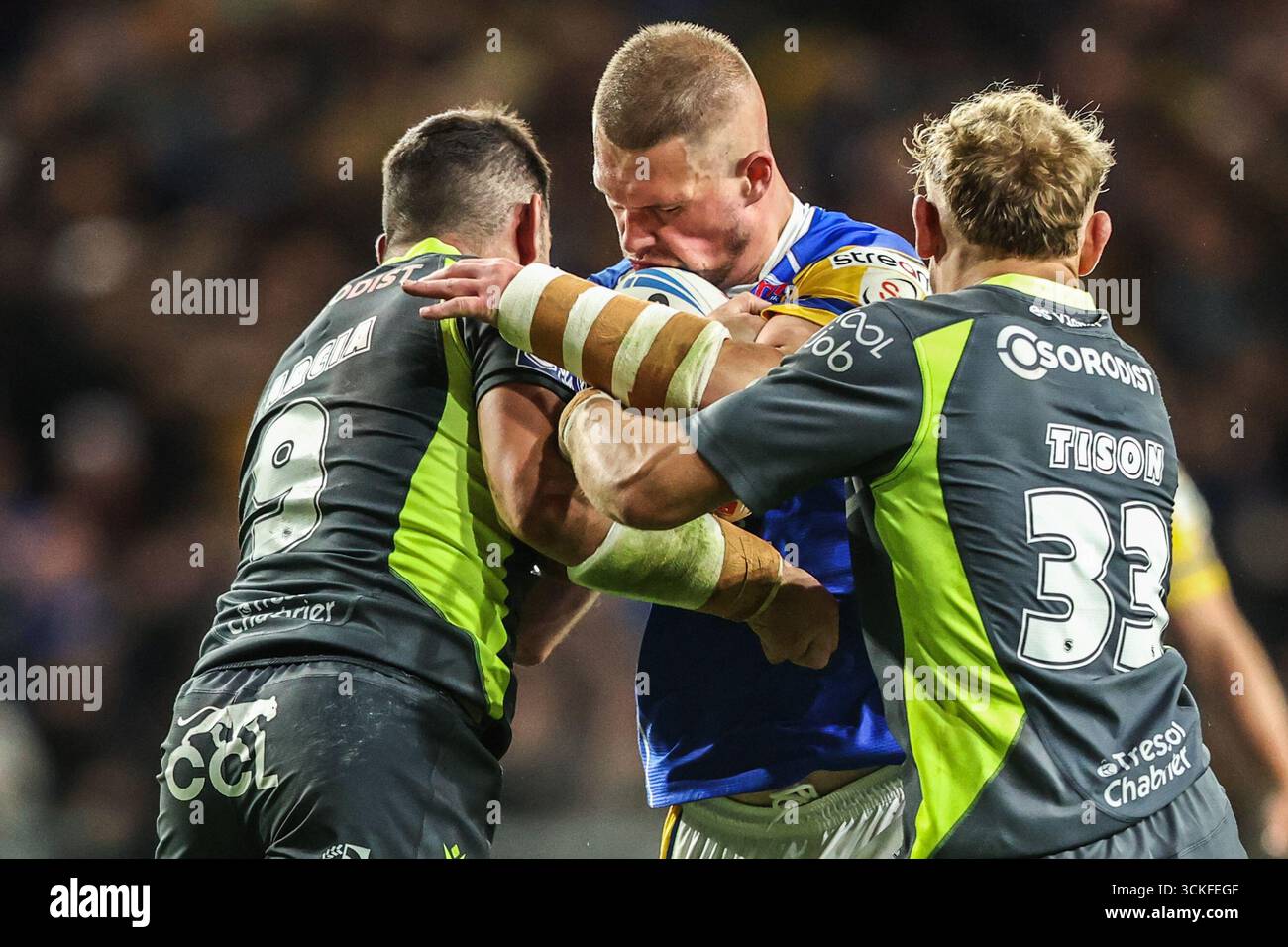 Tom Holroyd of Leeds Rhinos is tackled by Benjamin Garcia of Catalan ...
