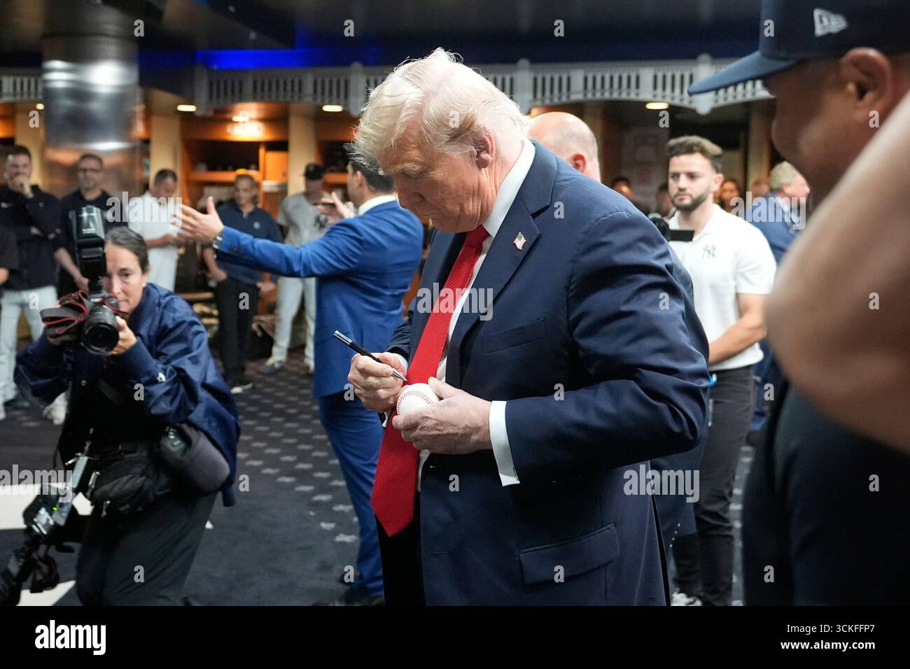 President Donald Trump signs a baseball in the New York Yankees locker ...