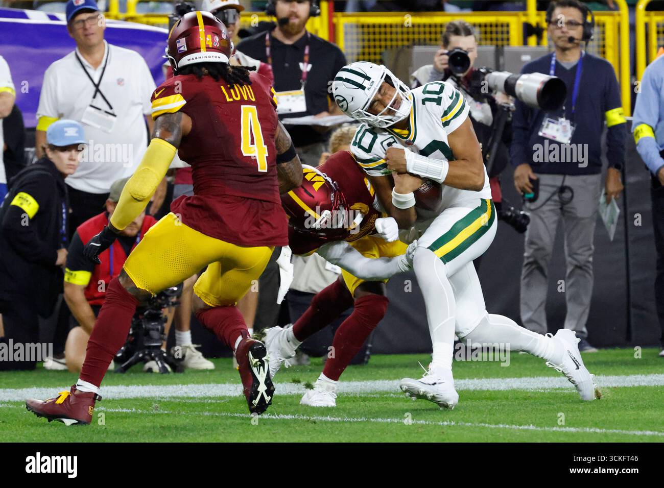 Green Bay Packers quarterback Jordan Love (10) is hit by Washington Commanders cornerback Trey ...