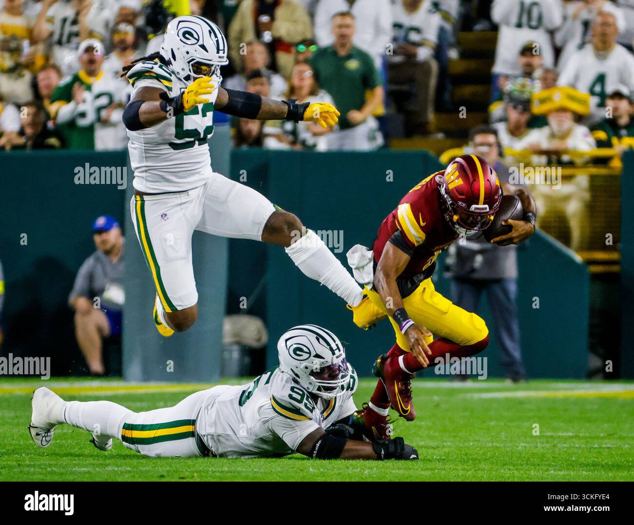 Washington Commanders quarterback Jayden Daniels (R) scrambles away from Green Bay Packers ...
