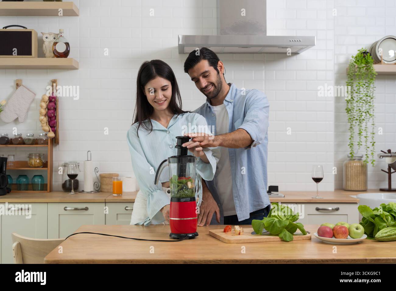 Smiling couple blending vegetables and fruits in modern kitchen using ...