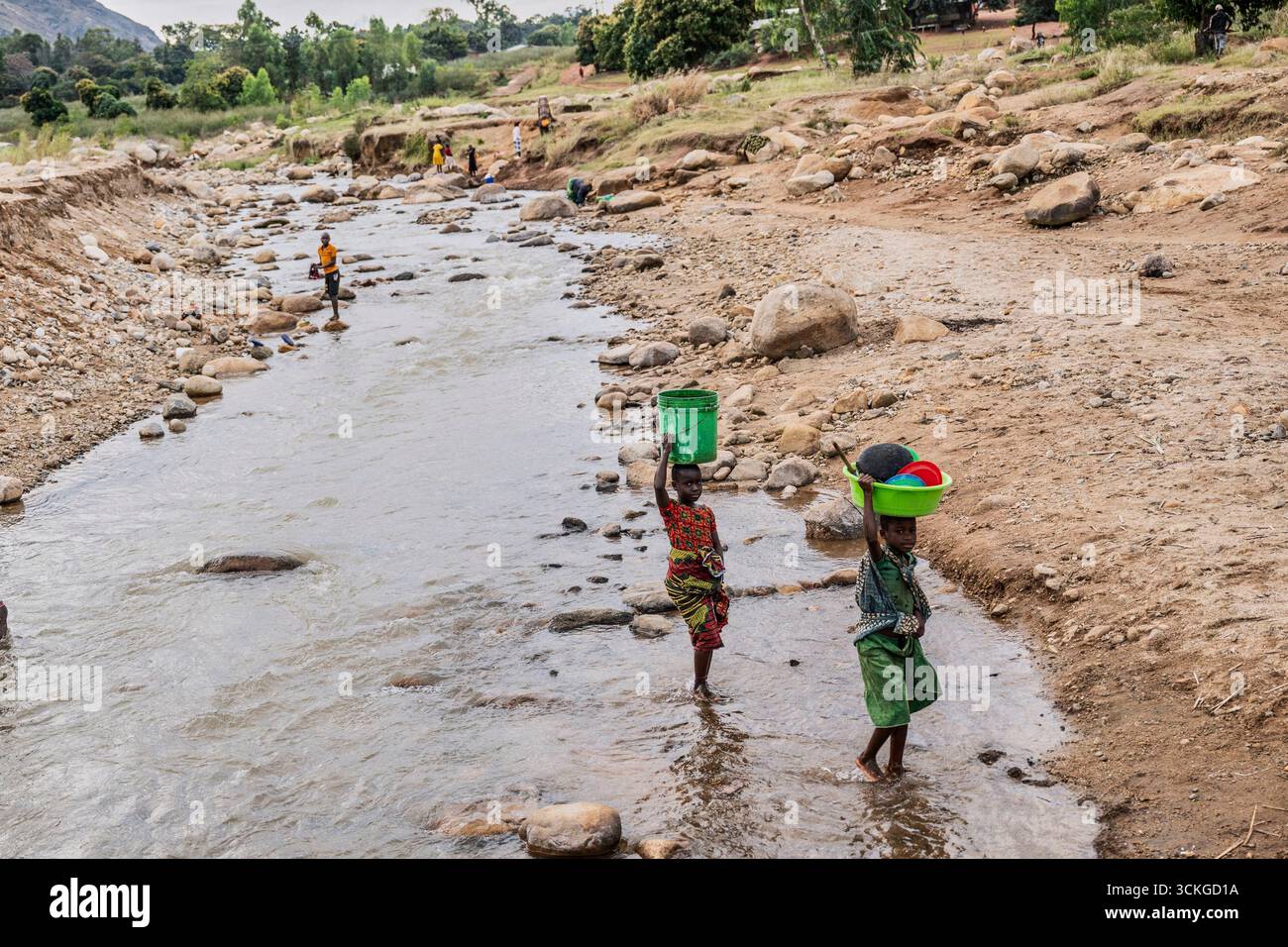 Children carry pots of water and dishes at a river in Mulanje, southern ...