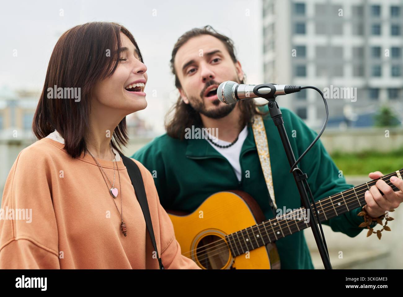Caucasian young woman singing into microphone next to Caucasian young ...
