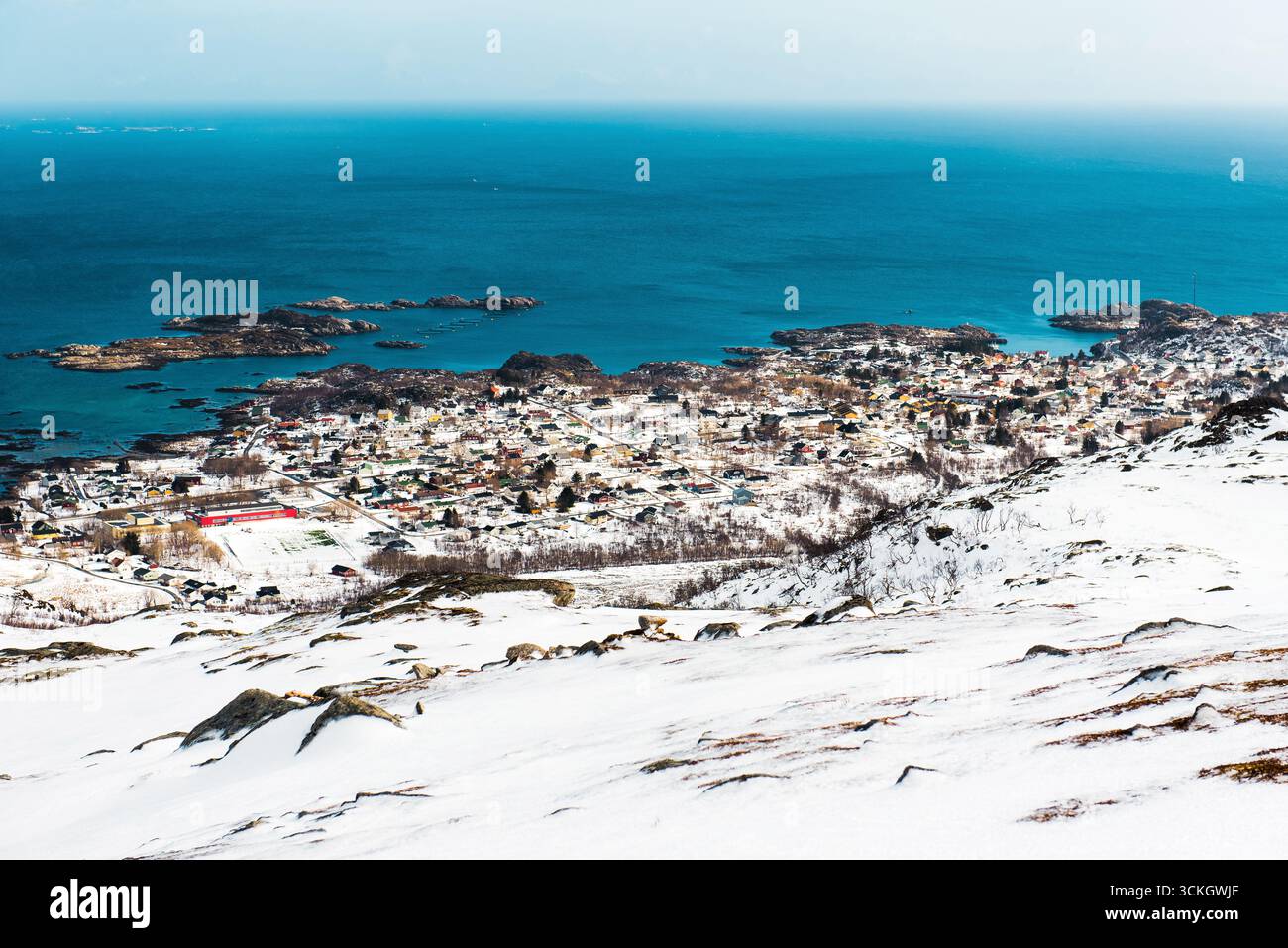 Aerial view of a snowy coastal town with scattered islands and blue sea ...