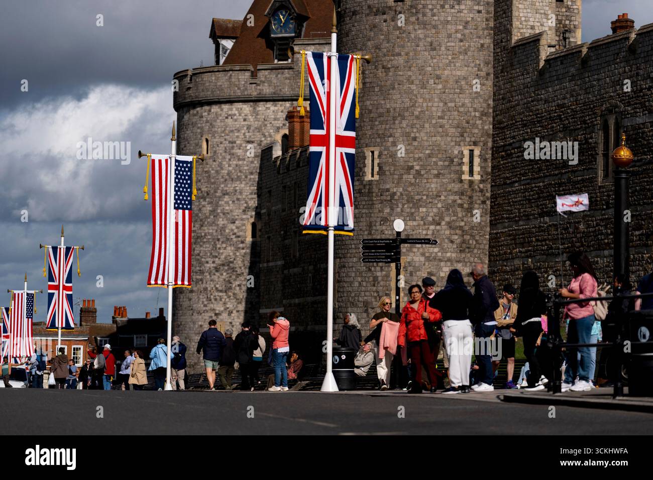 People walk past flags of the United Kingdom and the United States of ...