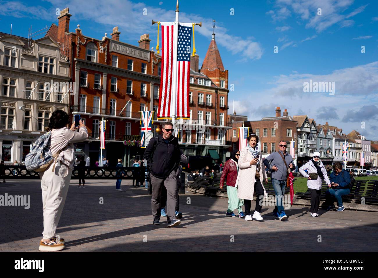 People walk past flags of the United Kingdom and the United States of ...