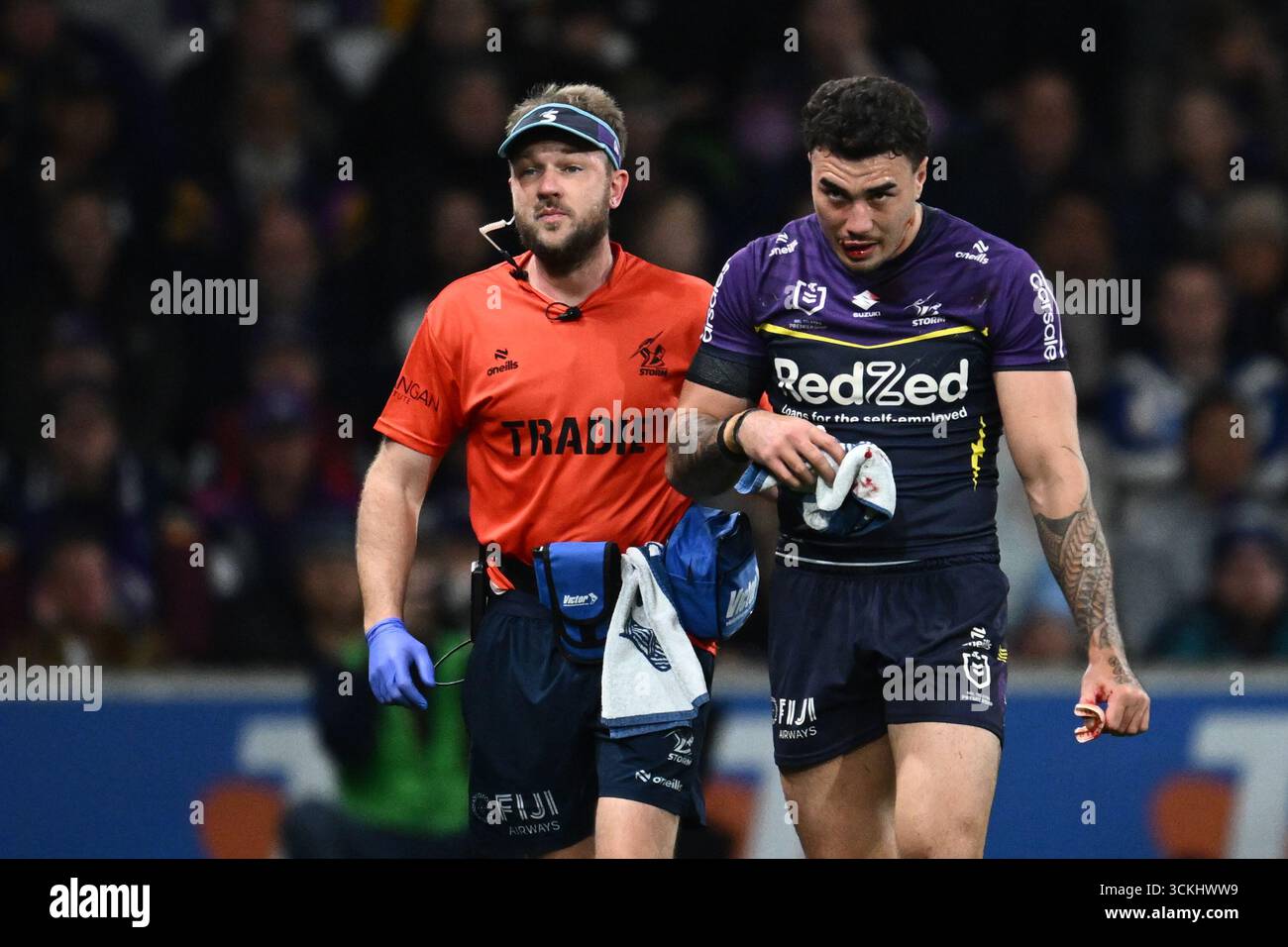 Joe Chan of the Storm is assisted by a trainer during the NRL ...