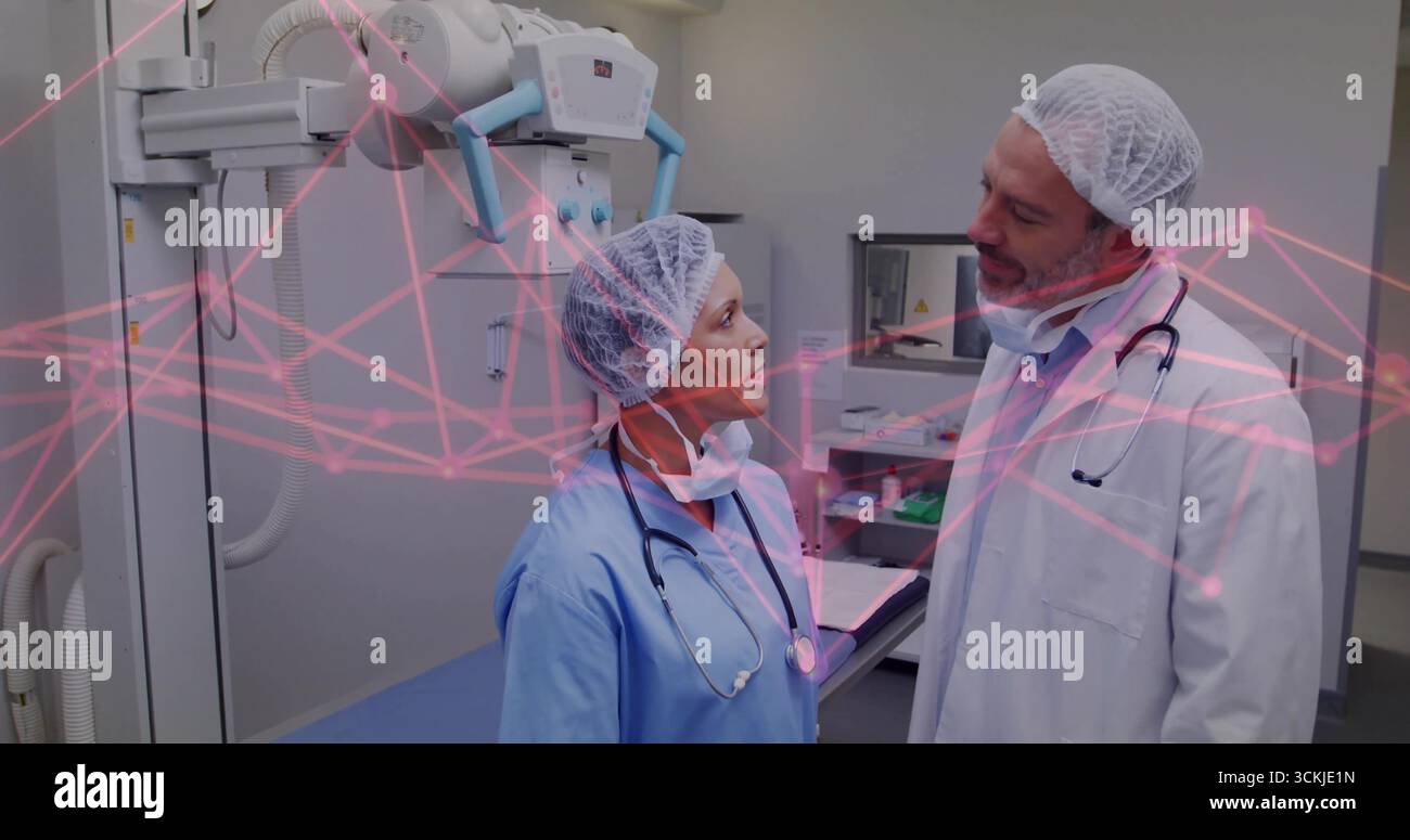 Doctor and nurse analyzing X-ray scan under ceiling-mounted tube in ...