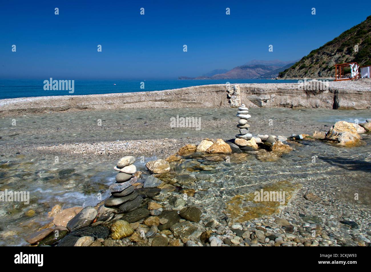 Pile di sassi in equilibrio lungo un ruscello di acqua limpida nella ...