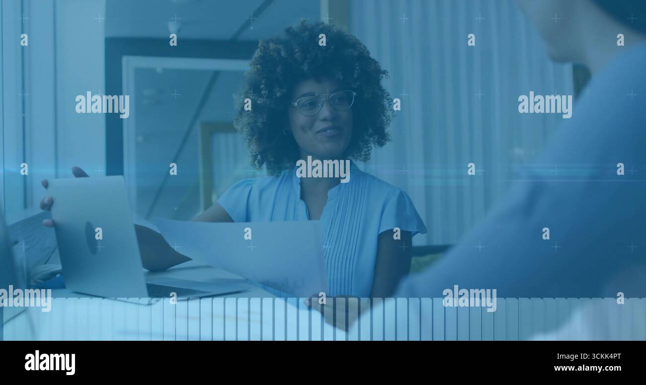 Curly-haired woman wearing light blue blouse handing document in office ...