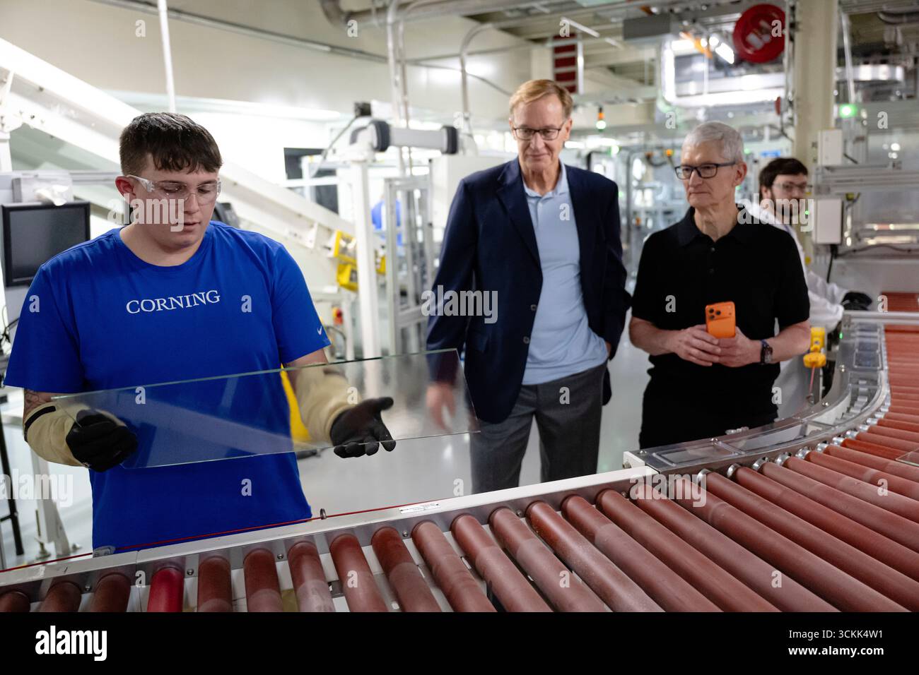 A quality control employee displays a section of glass while Apple CEO ...