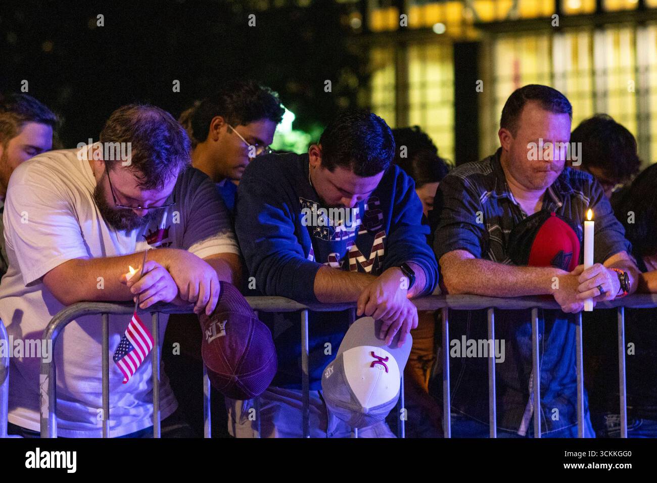 Attendees bow their heads in prayer during a vigil for Charlie Kirk at ...