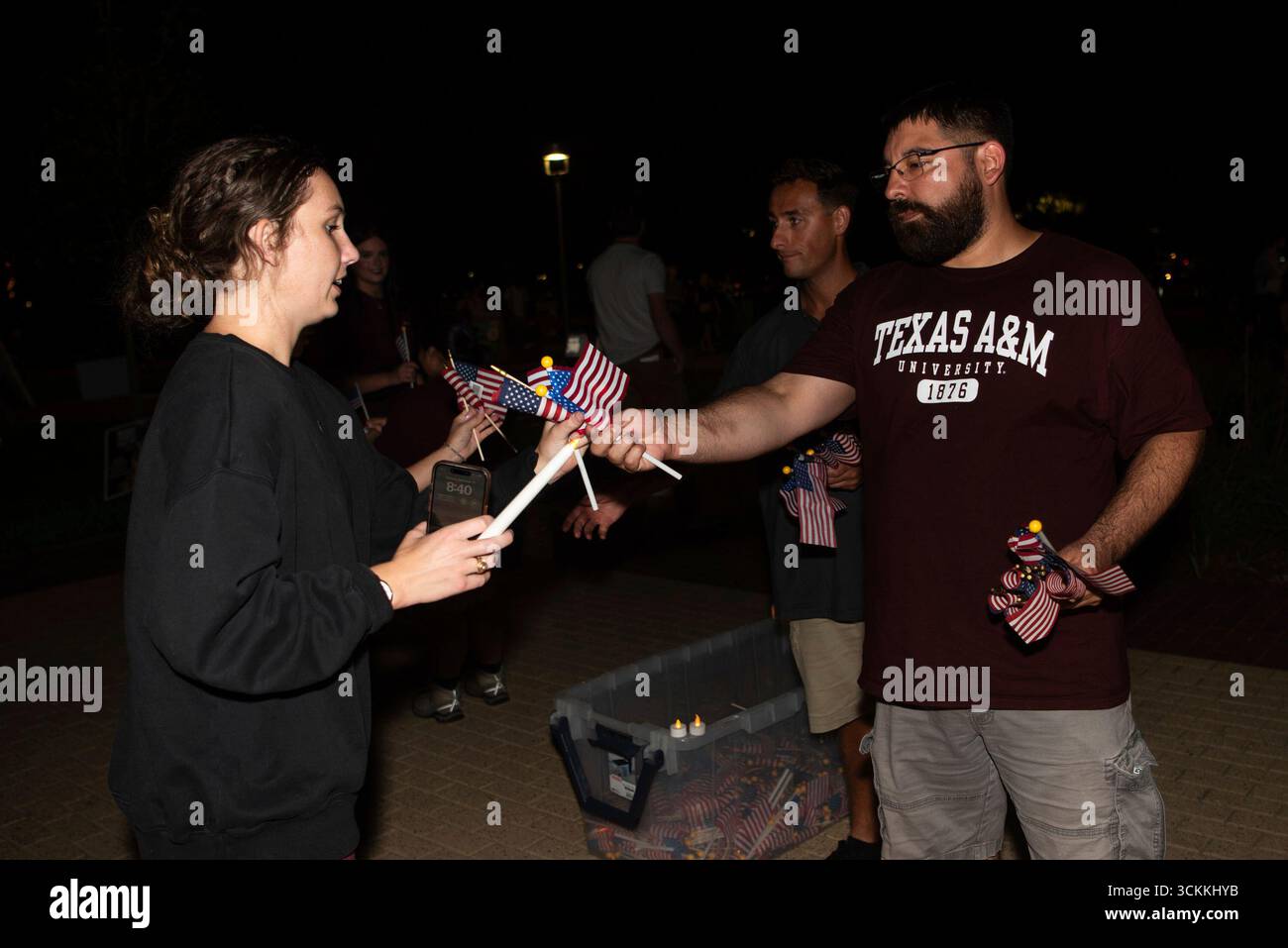 People gather and hand out flags prior to a vigil for Charlie Kirk at ...