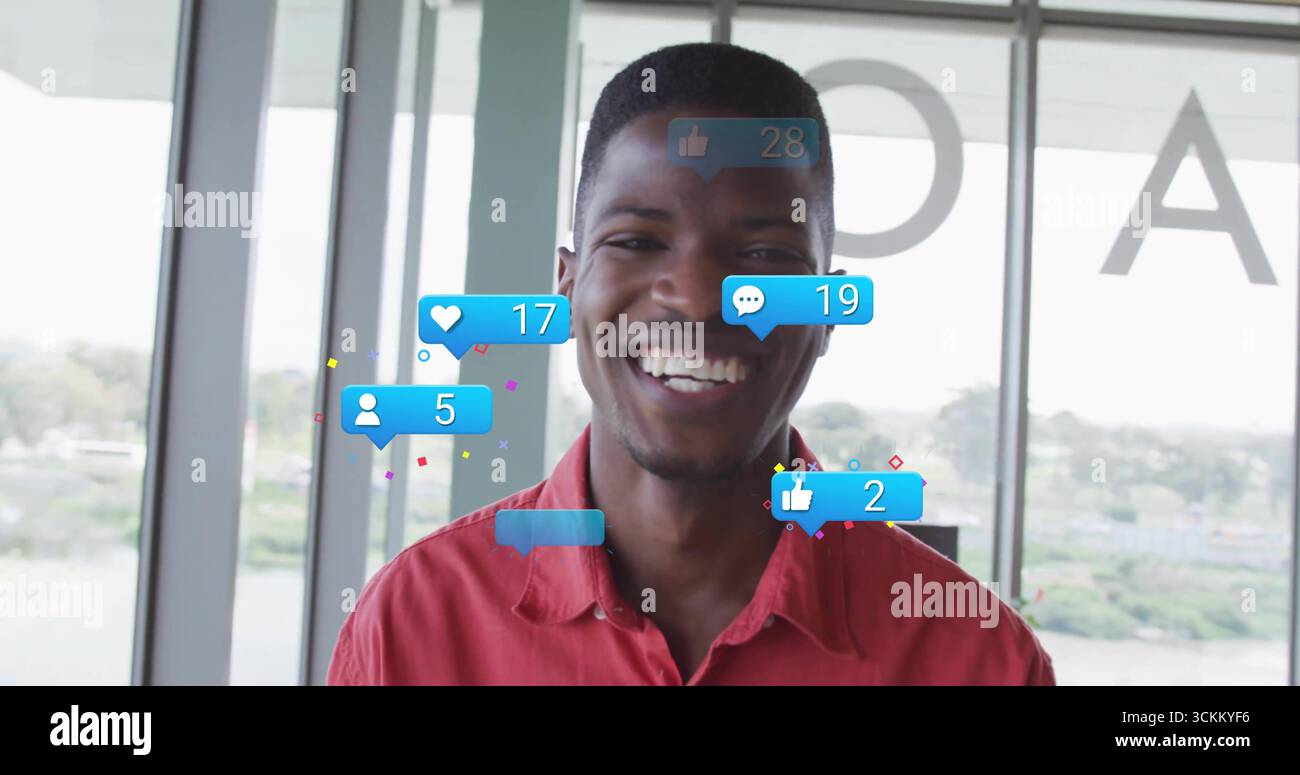 Smiling male influencer standing in modern office by glass windows with ...