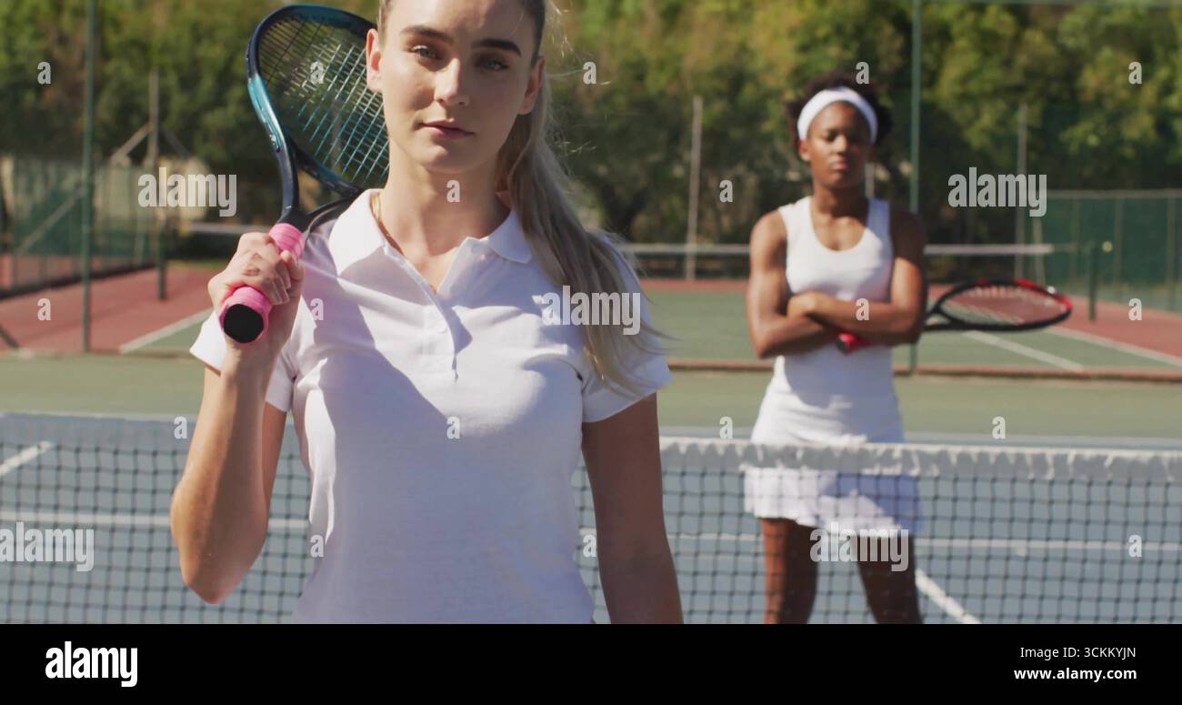 Standing tennis player wearing white gear shouldering racket on outdoor ...