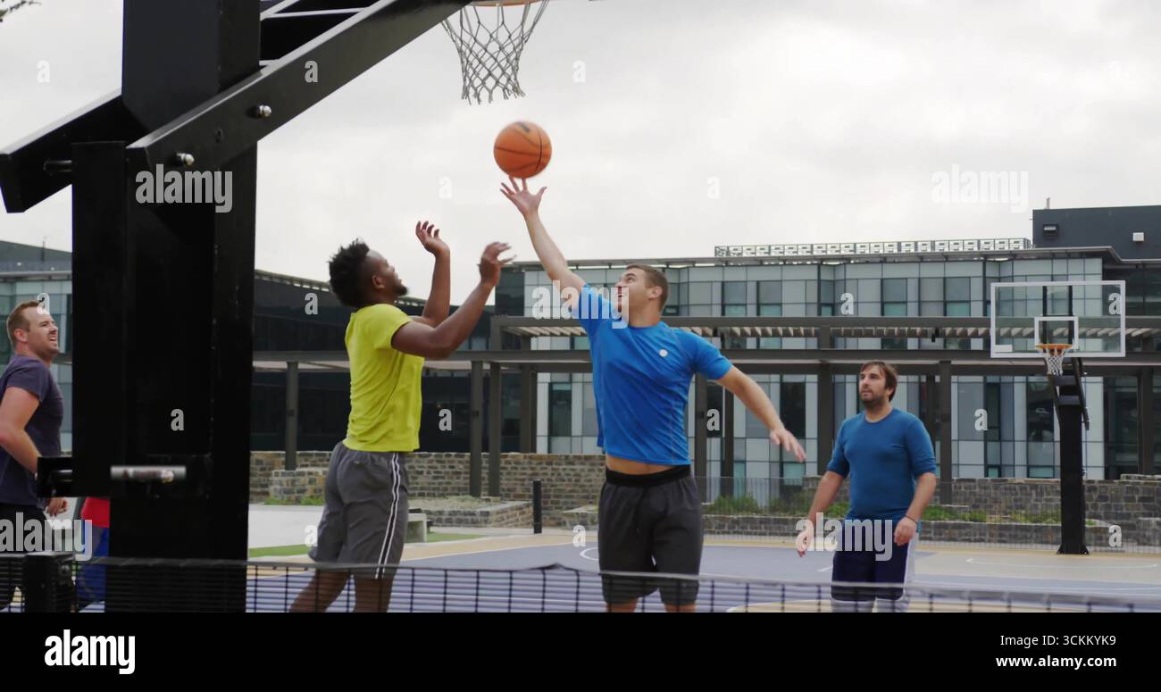 Playing four men jumping for basketball under hoop on hardcourt, with ...