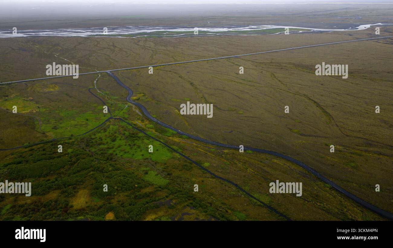 Drone perspective of a flat Icelandic terrain featuring a straight road ...