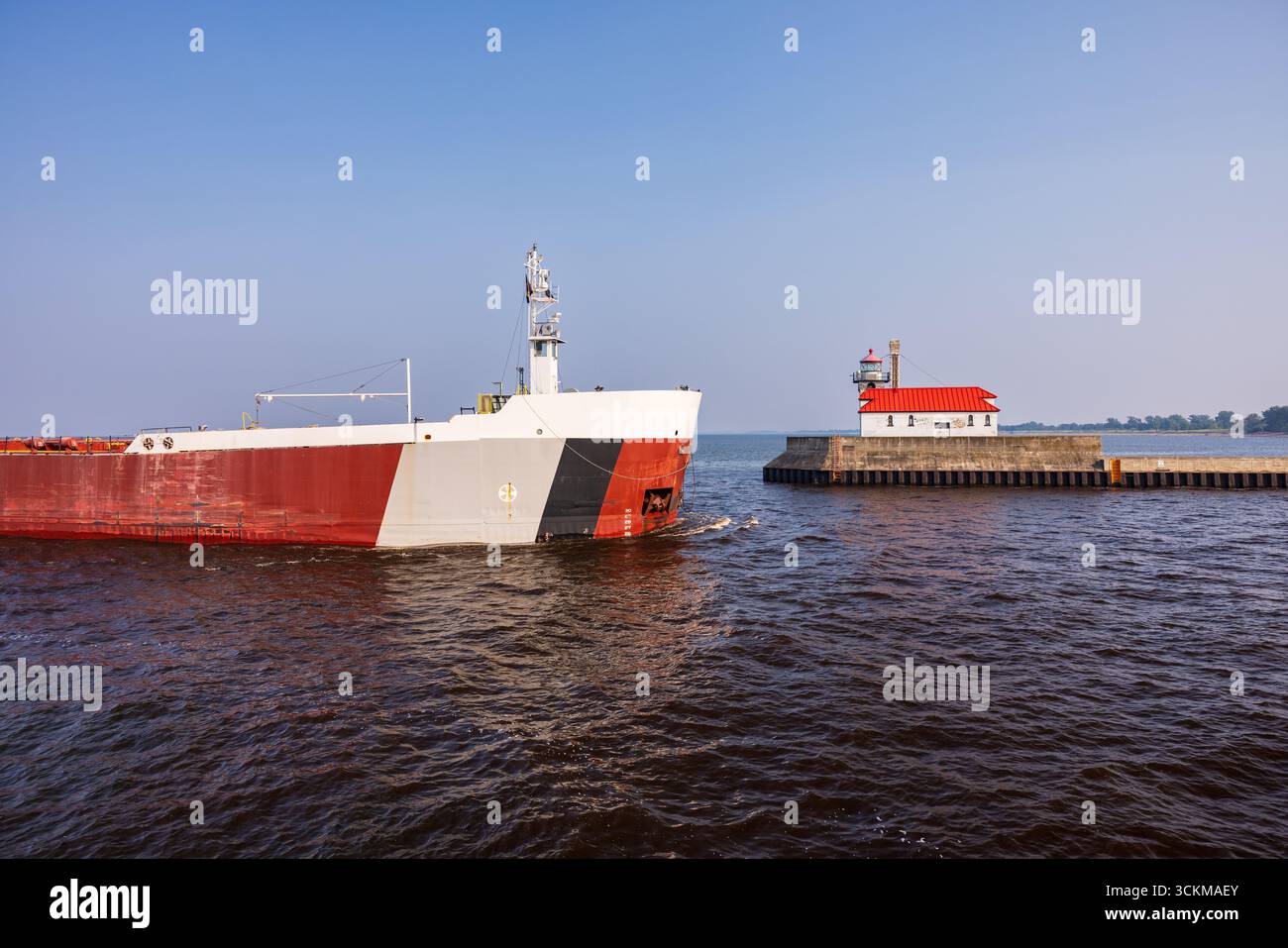 A freighter ship entering a canal by a lighthouse on Lake Superior ...