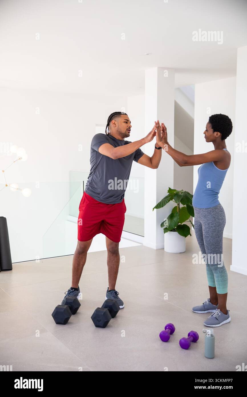 Diverse training partners pressing palms together near glass railing in ...