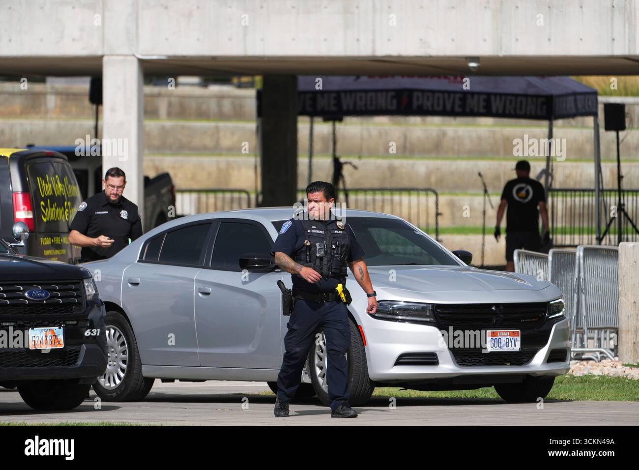 Police officers look on as a worker cleans up the scene at Utah Valley ...