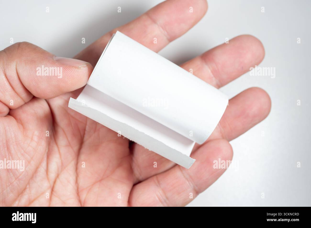 A hand holding a thermal paper roll, symbolizing the direct skin ...