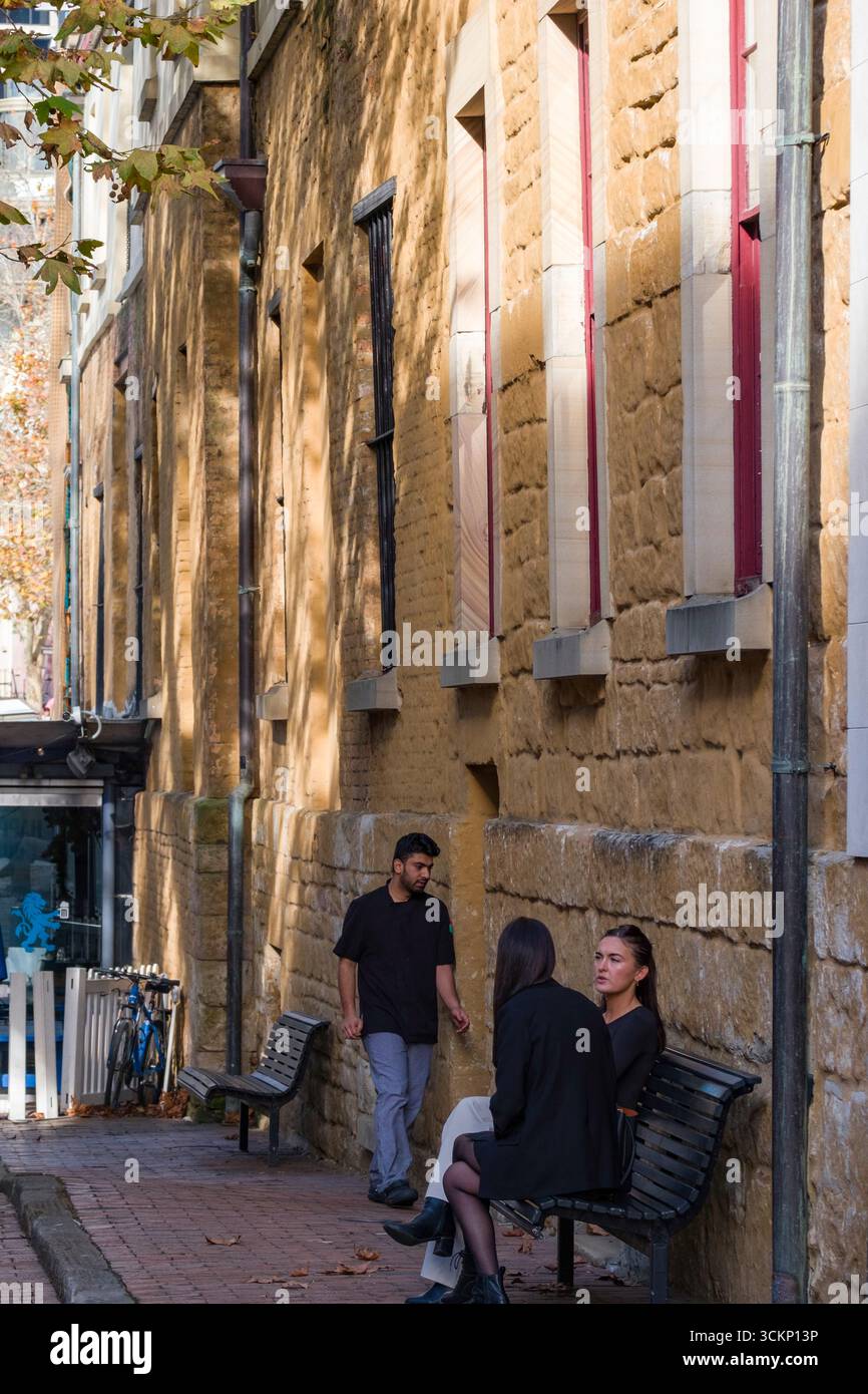 A lively urban street featuring a rustic stone building, people ...