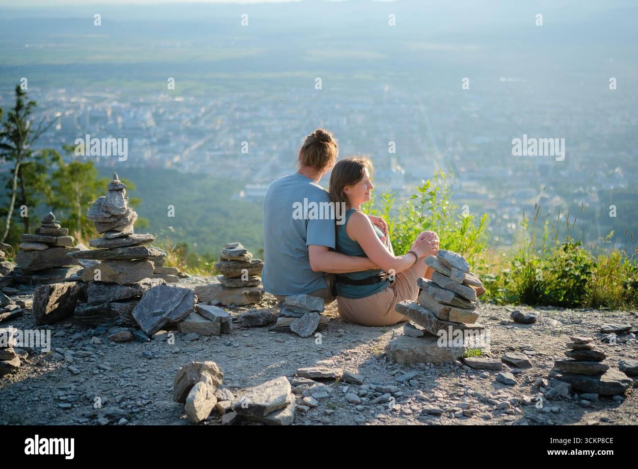 Man and woman sitting embraced from behind while enjoying spectacular ...