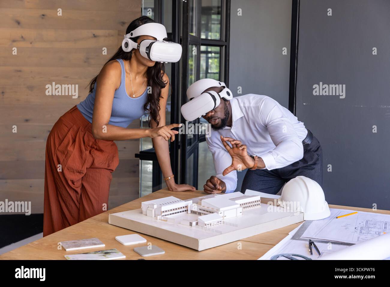 Diverse colleagues wearing vr headsets pointing at scale model ...