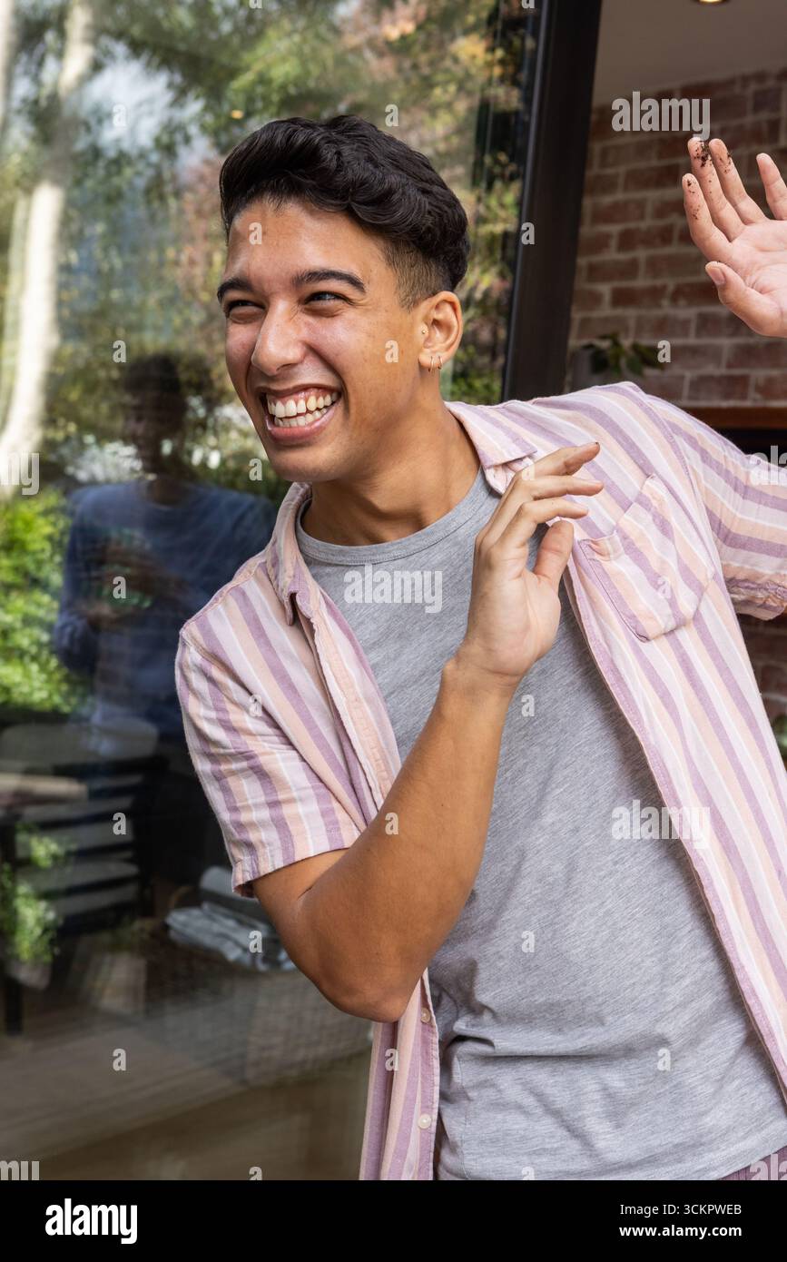 Adult male posing by glass door gesturing showing brick wall wood floor ...