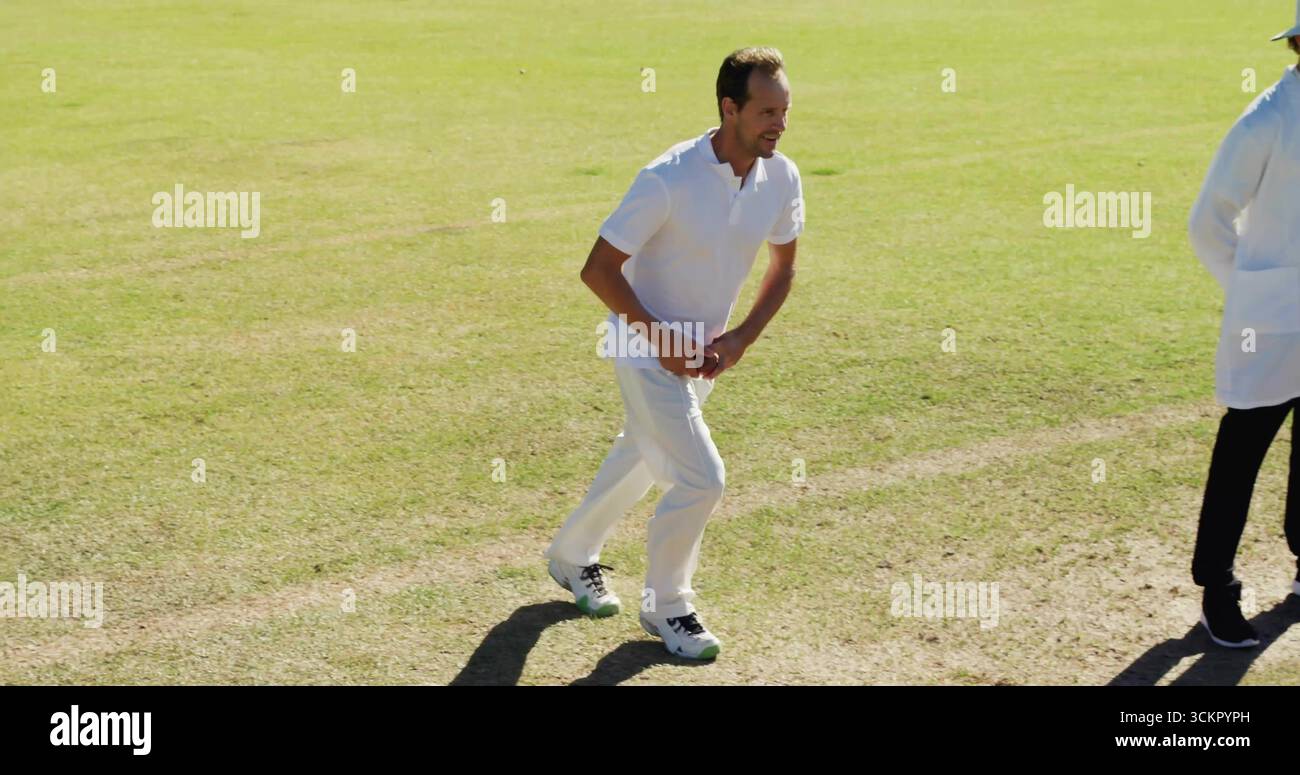 Running cricketer in uniform preparing to bowl on cricket pitch with ...