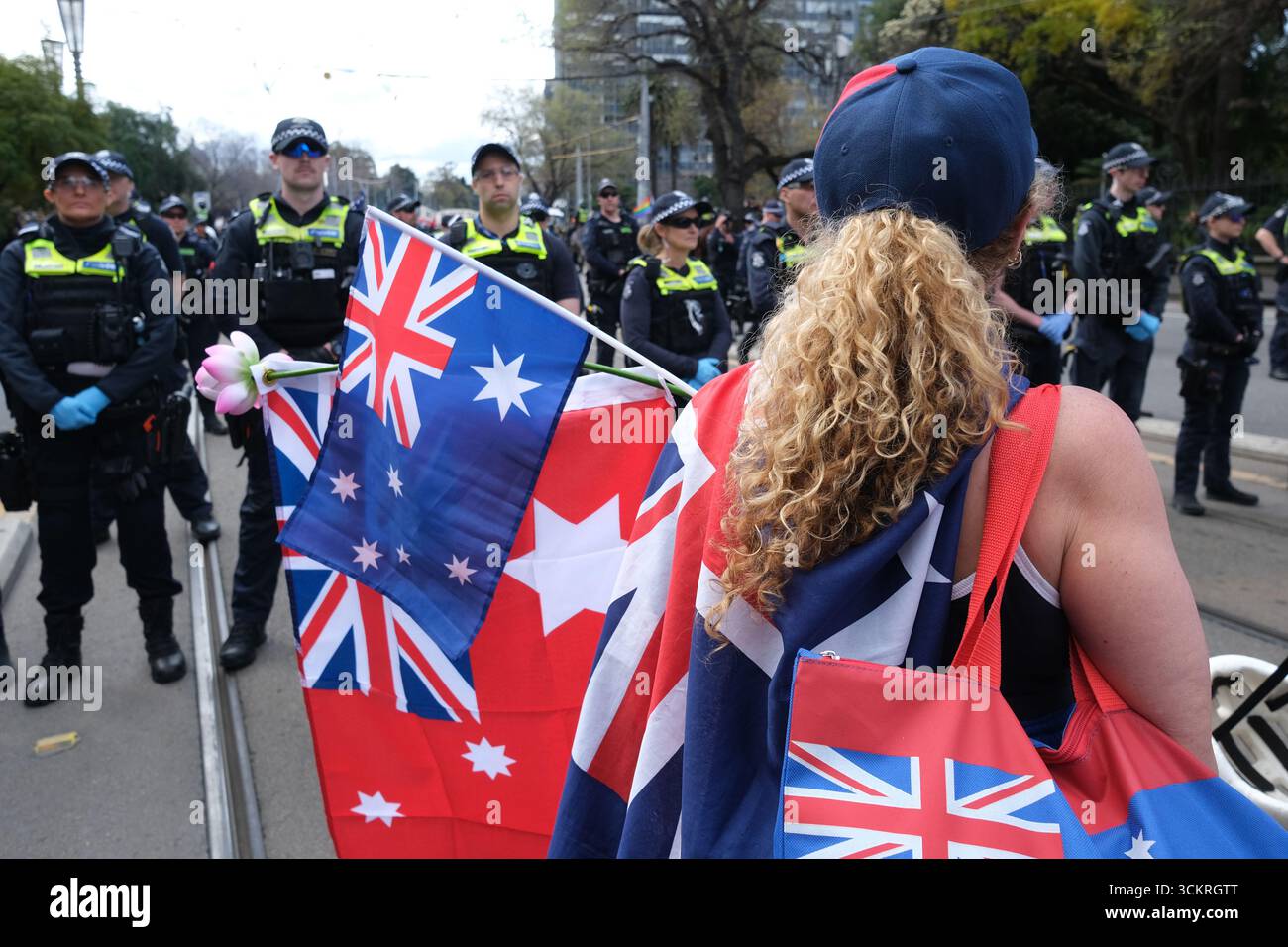 A young woman wearing and carrying the Australian flag confronts police ...