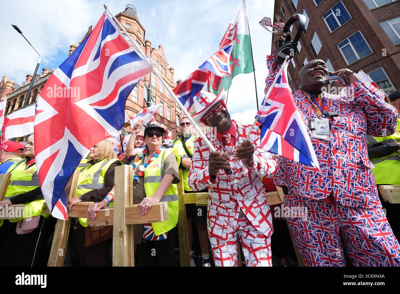 A man wearing a St George Cross suit, surrounded by people holding ...