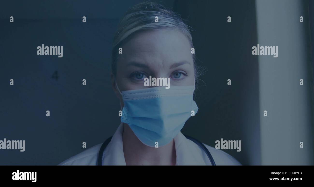 Standing doctor adjusting surgical mask and lab coat in hospital hall ...