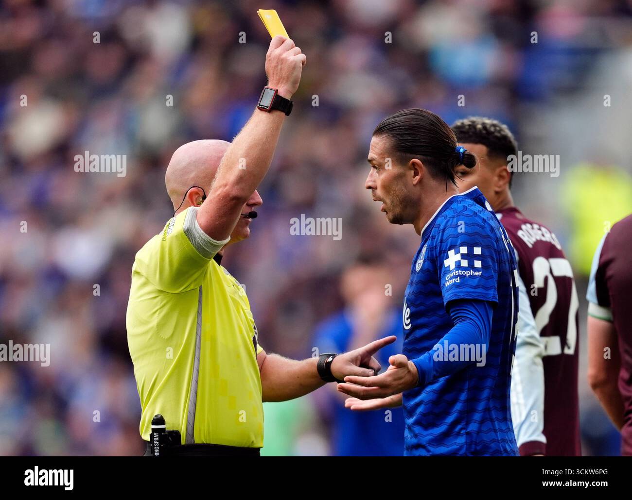 Referee Simon Hooper shows a yellow card to Everton's Jack Grealish ...