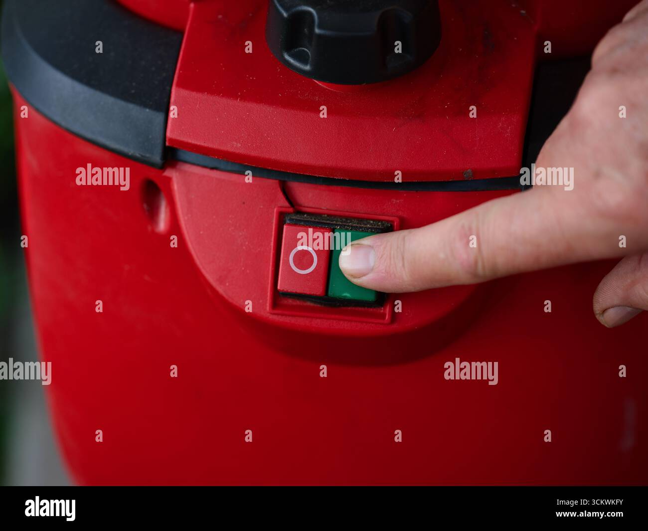 Close-up shot of a person finger pressing the green On button on a red ...
