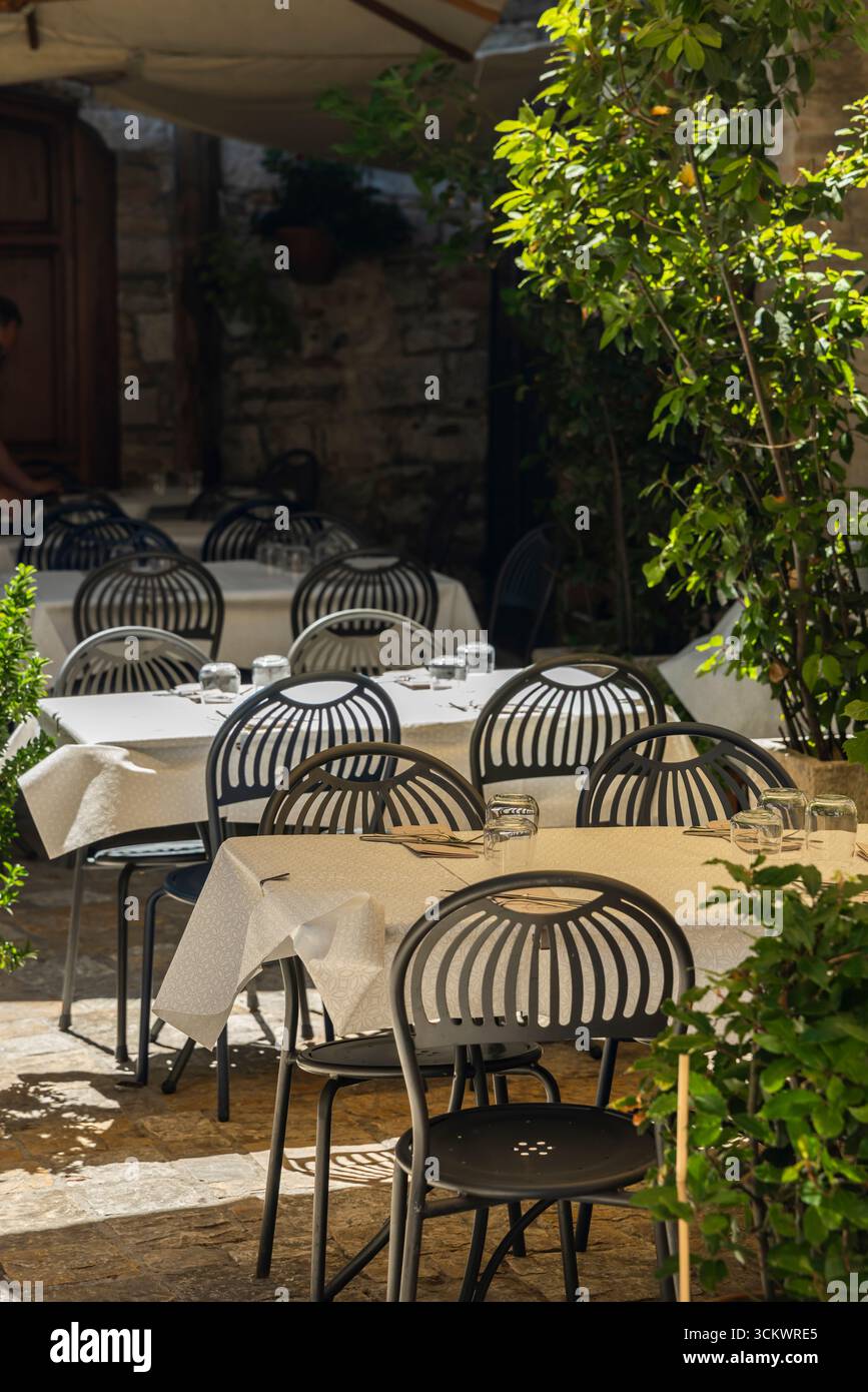 Empty tables and chairs are set up outside a restaurant in Assisi ...