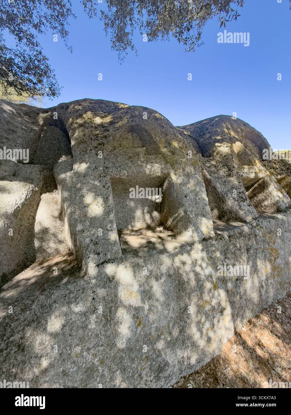 Ancient rock-cut altar with multiple niches under oak trees in Sardinia ...