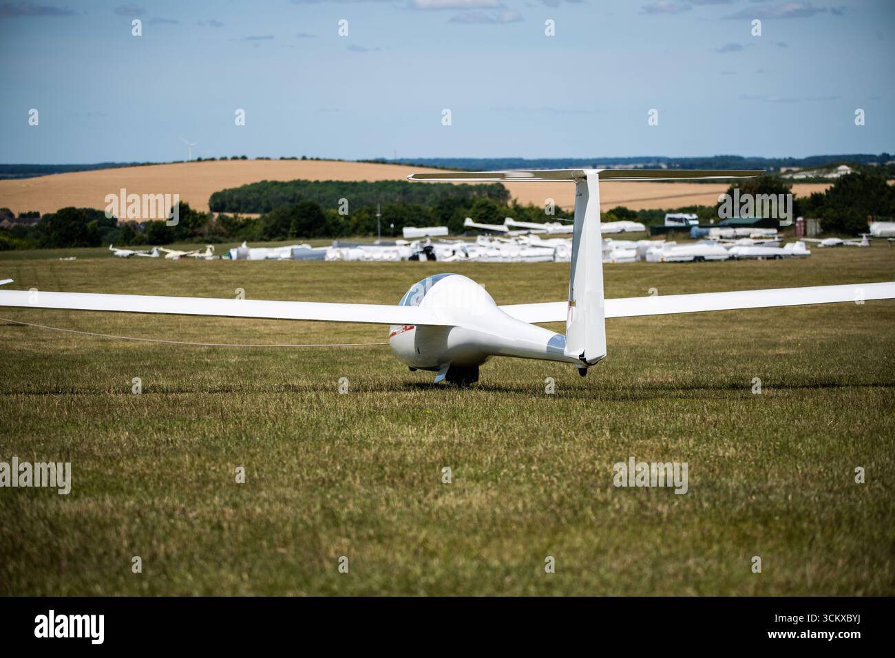 White two-seat glider with T-tail on a grass runway at an airfield ...