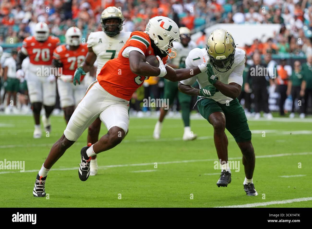 Miami wide receiver Joshua Moore, left, holds off South Florida ...