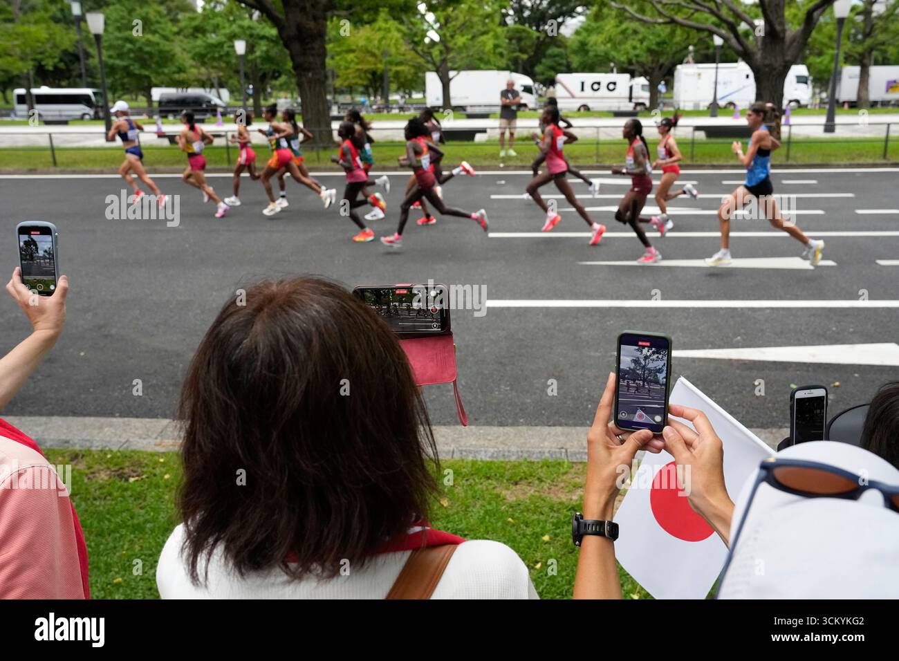 Spectators take photos of runners in the women's marathon at the World ...
