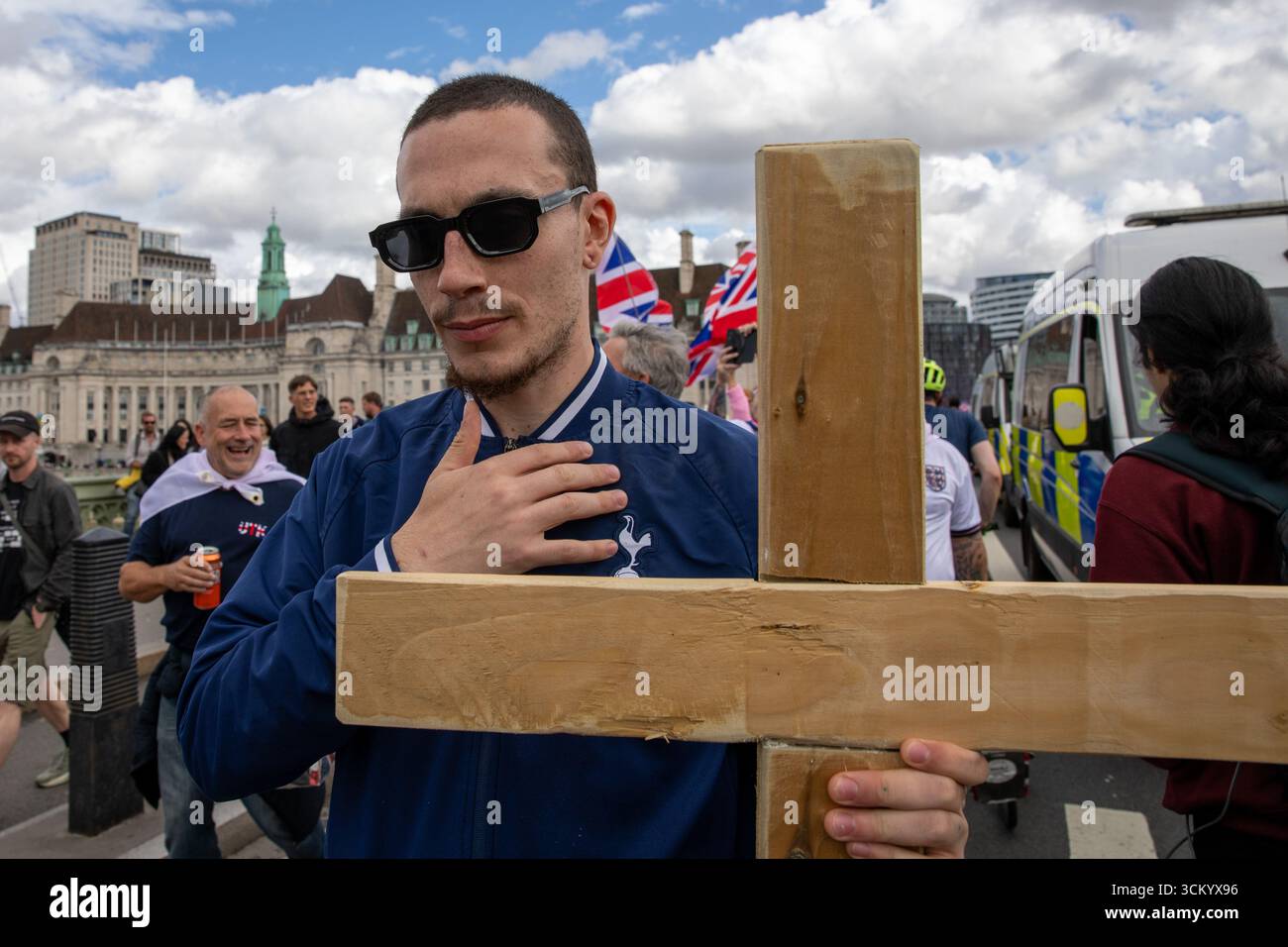 A protestor holds a wooden cross during a demonstration. The Unite the ...