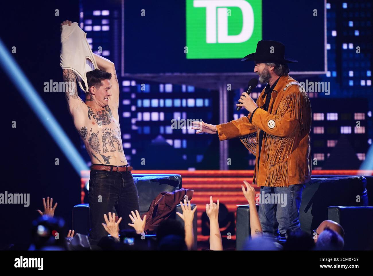 Cameron Whitcomb takes off his shirt as host Tom Green looks on as they ...