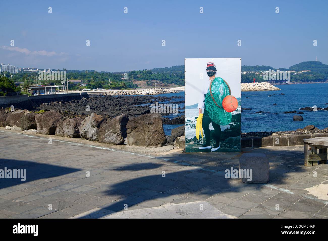 A photo cutout board of a Jeju haenyeo diver stands along the volcanic ...