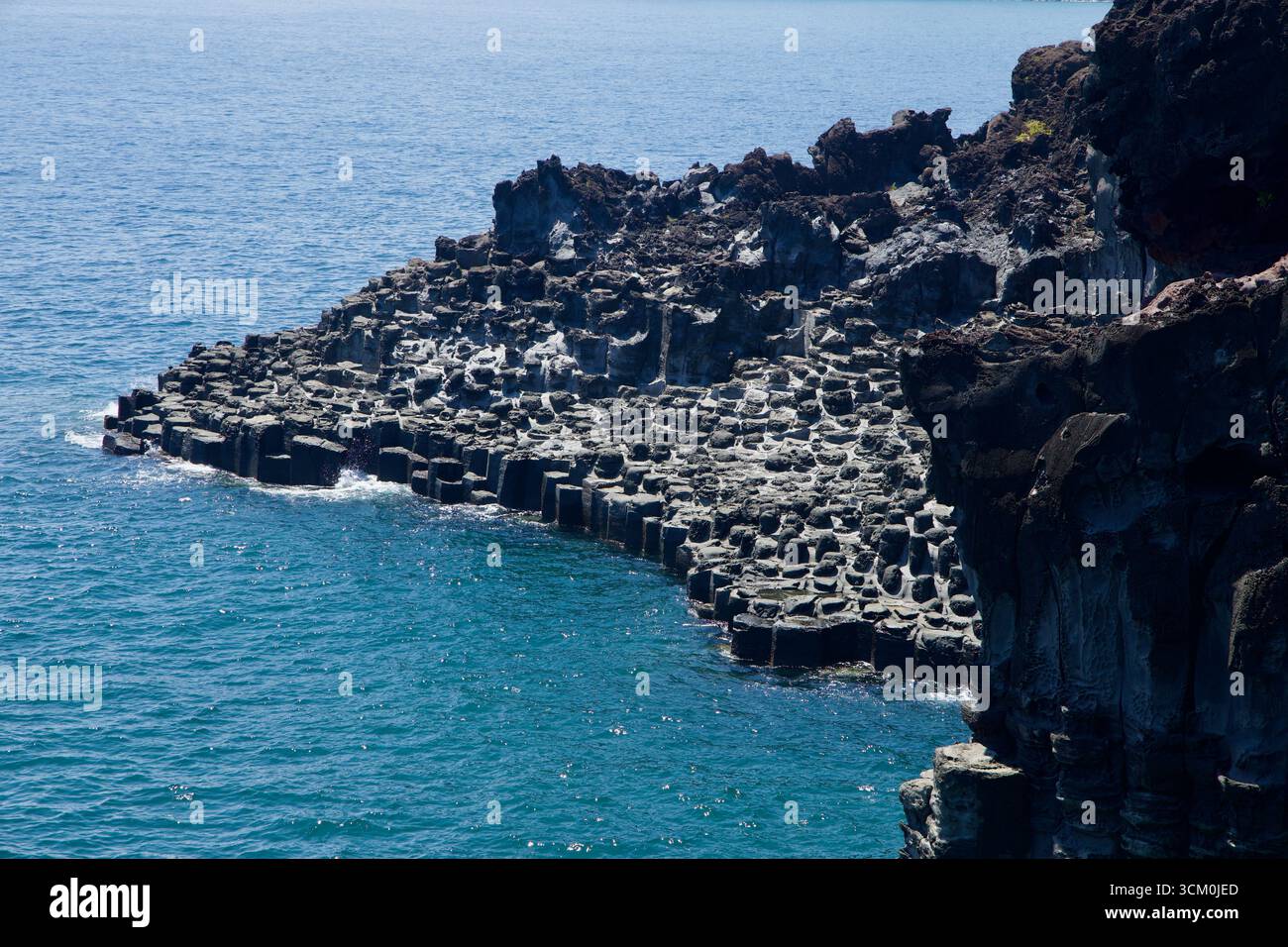 Stepped basalt shelves rise from the waterline at Daepo Jusangjeolli ...