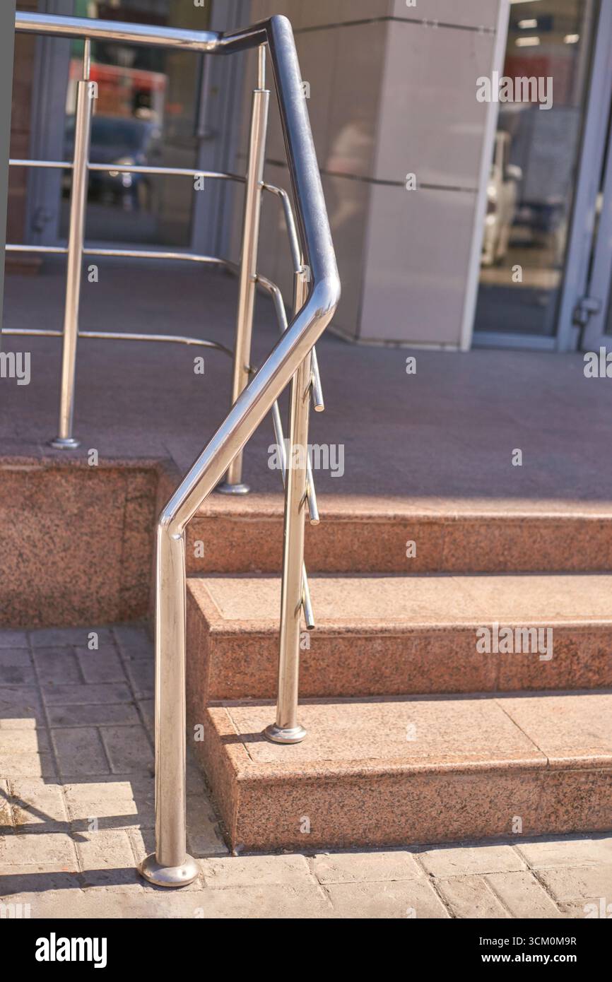 Stainless steel handrail on outdoor building steps with red stone ...