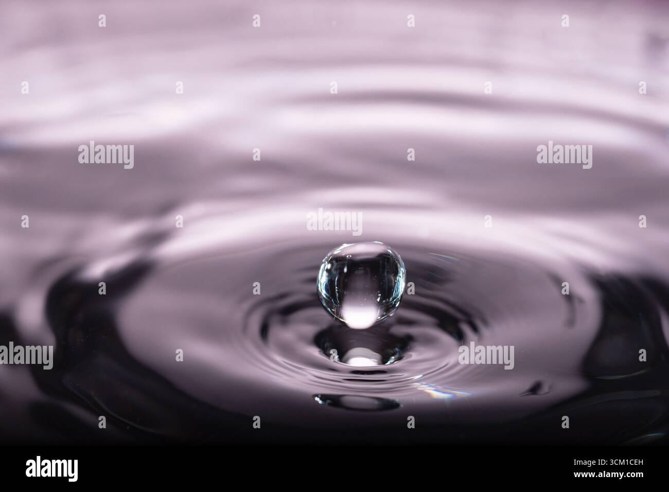 176.Water droplet rebounding above surface with concentric ripples ...
