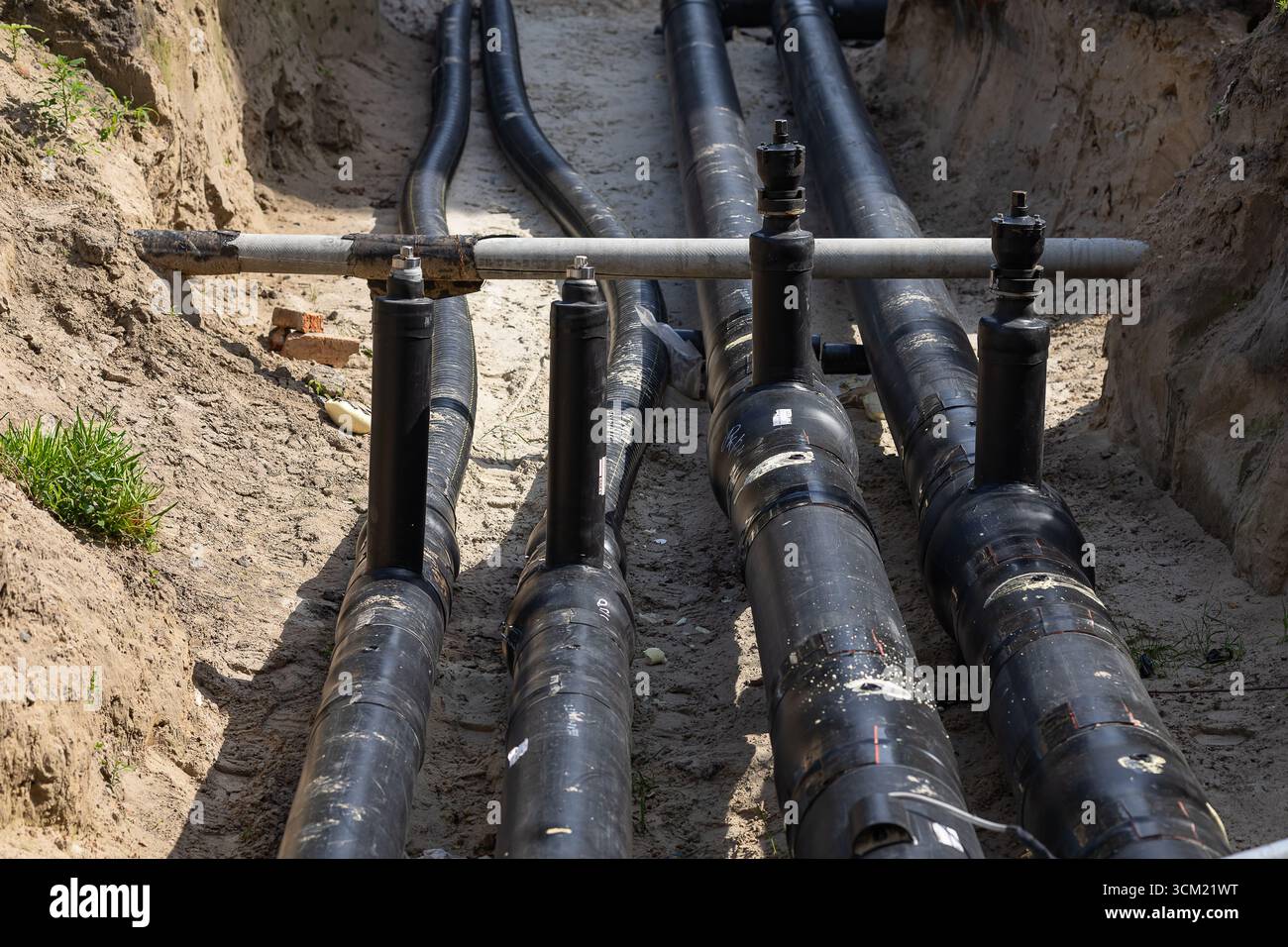 Large black plastic pipes in open trench during urban construction work ...