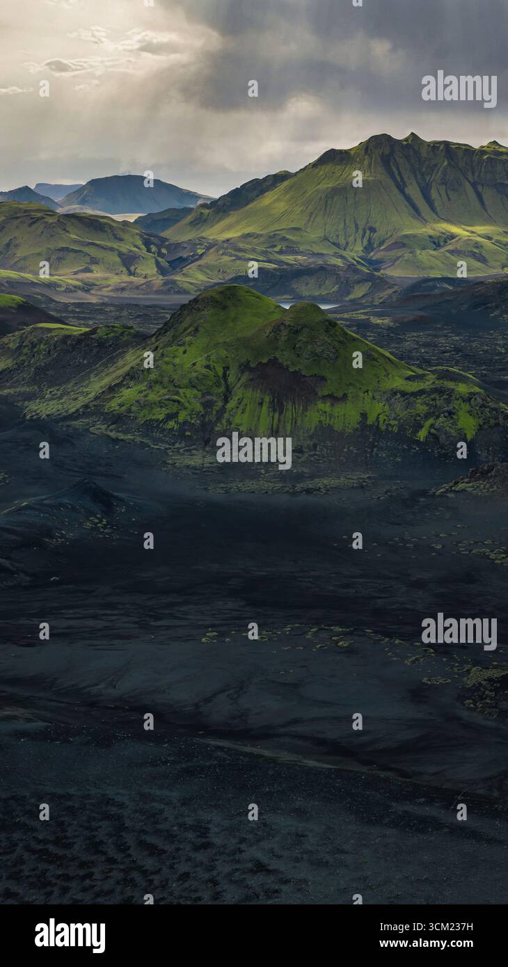 Aerial perspective of a moss covered volcanic hill surrounded by dark ...