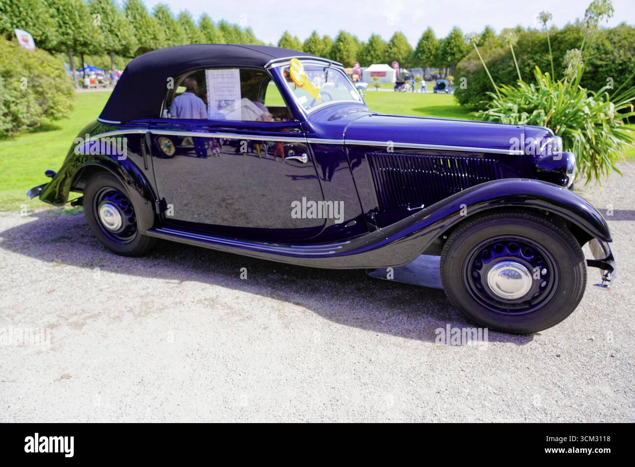 Classic car in side view, elegant design, at an event with trees in the ...